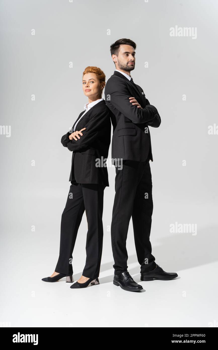 full length of confident redhead businesswoman standing back to back ...