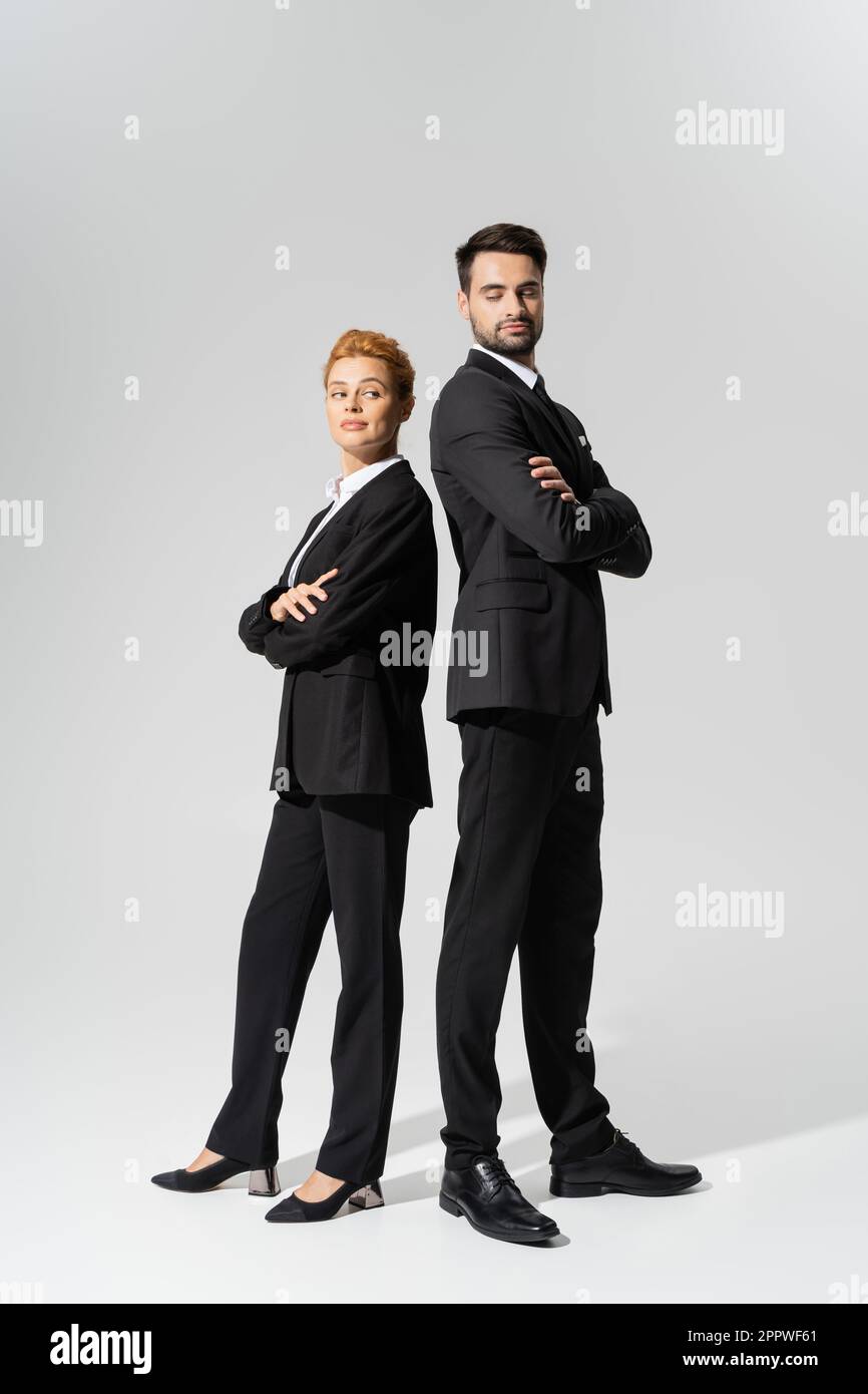 full length of incredulous business people standing back to back with ...