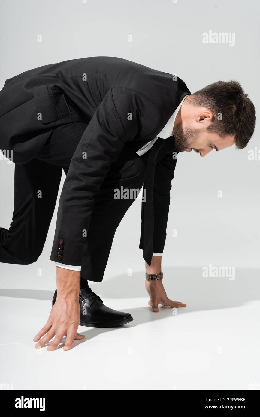 side view of purposeful businessman in black suit standing in low start ...
