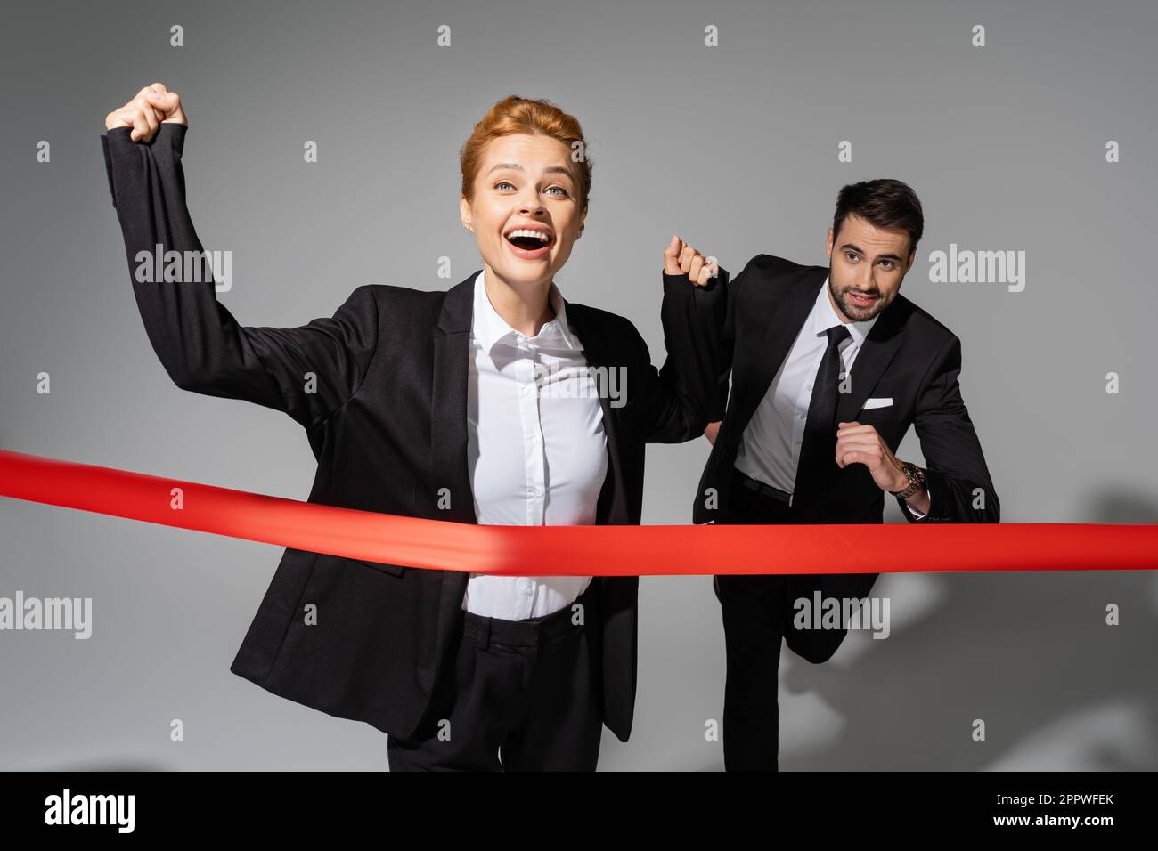 joyful businesswoman celebrating triumph near finish ribbon while ...