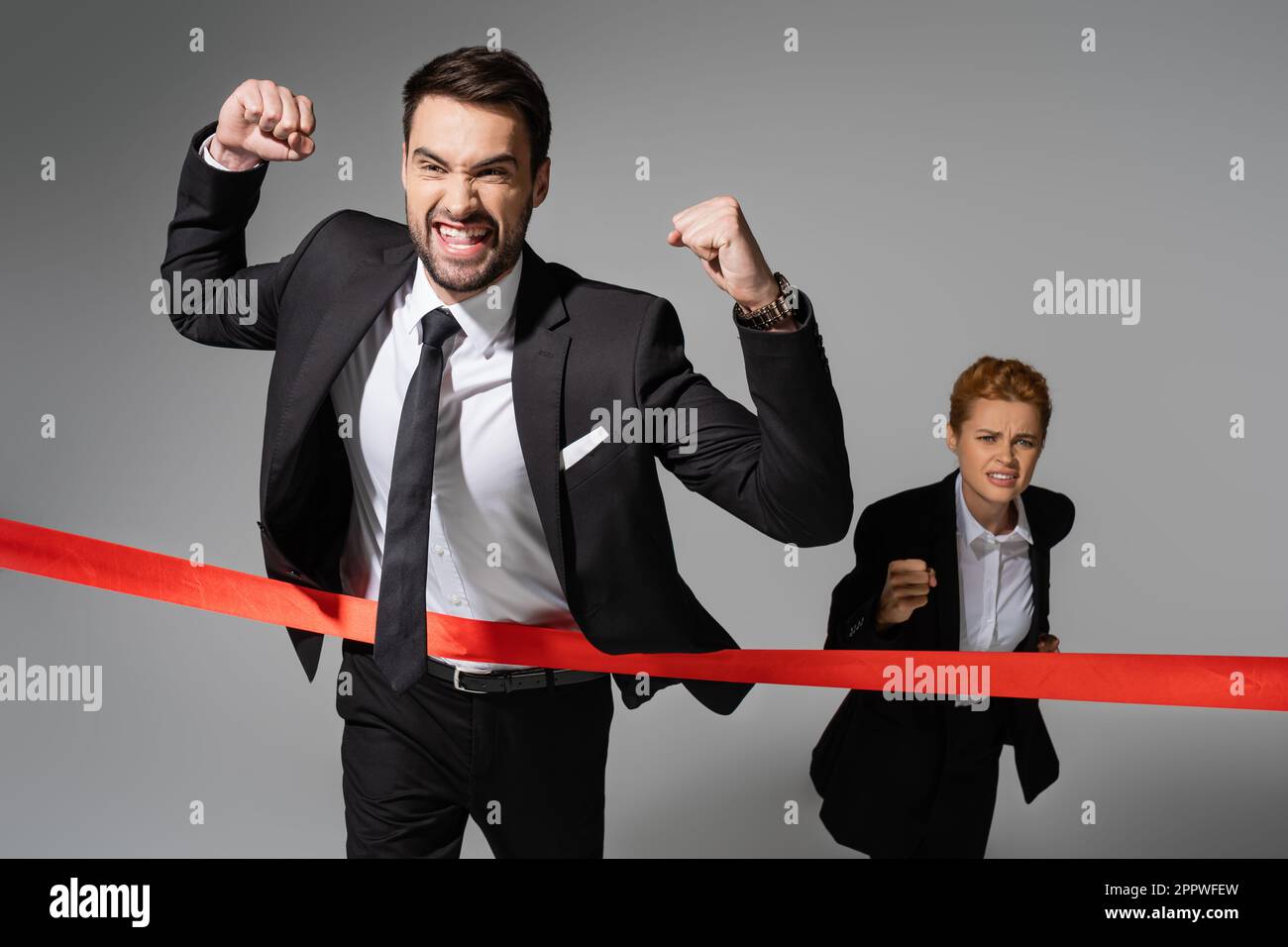 overjoyed businessman in black suit showing win gesture near sad woman ...