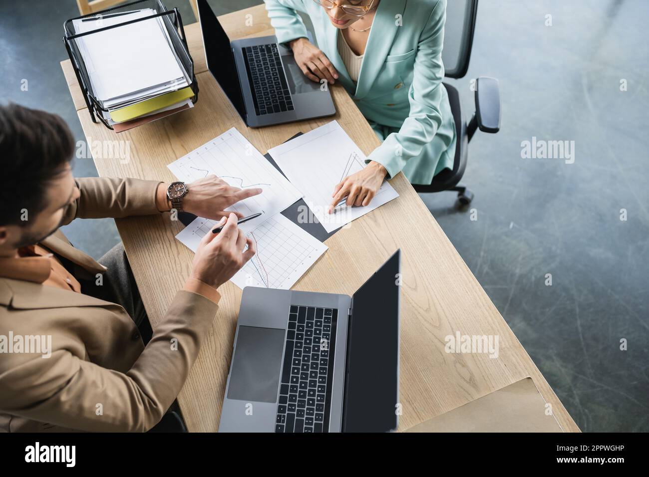 high angle view of business people pointing at infographics while ...