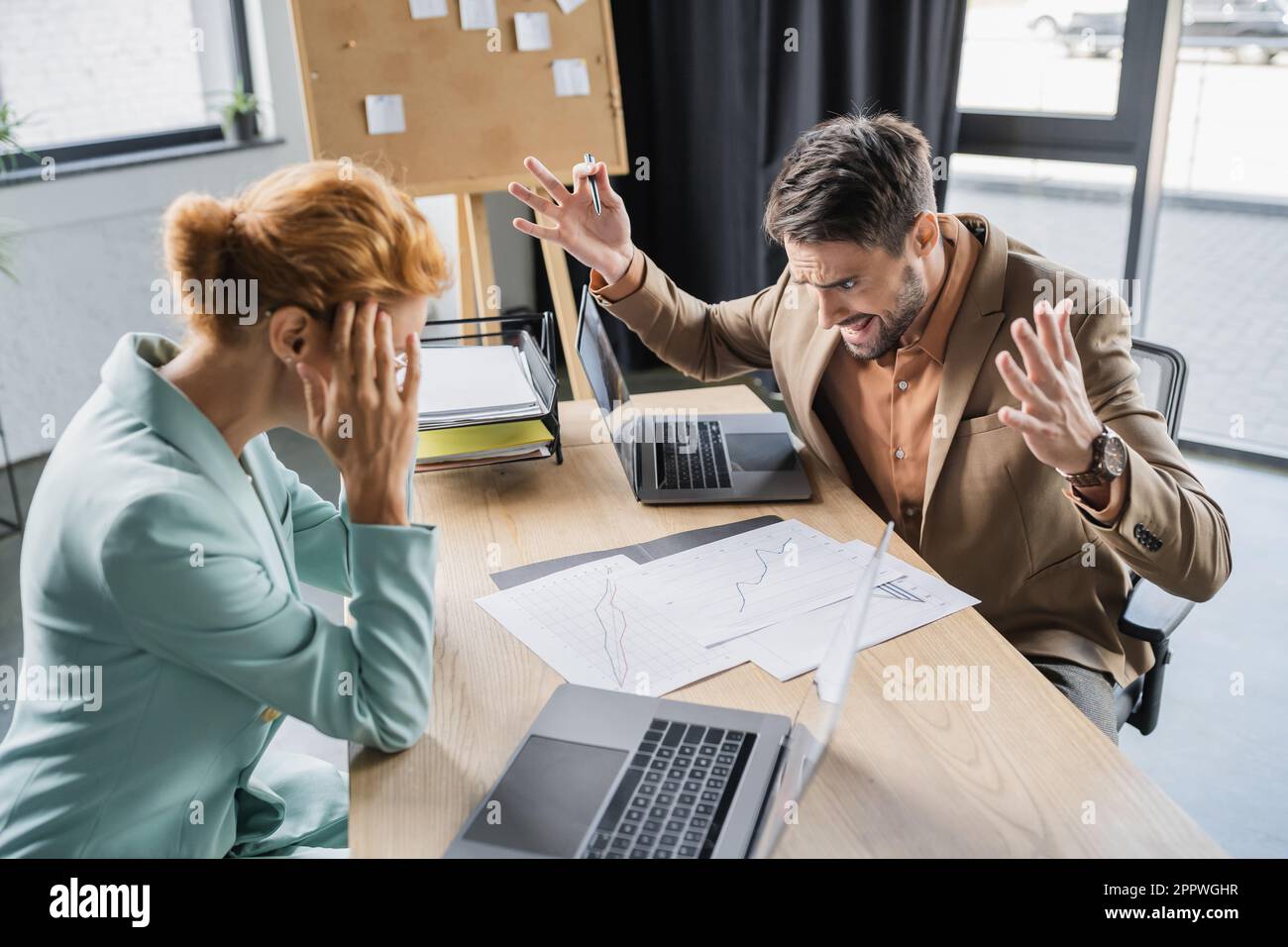 angry businessman shouting and gesturing near documents and redhead ...
