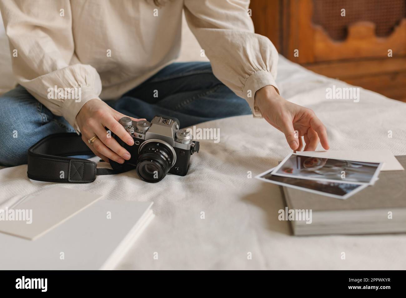 Close-up of a stylish woman sitting on bed with her camera looking at ...