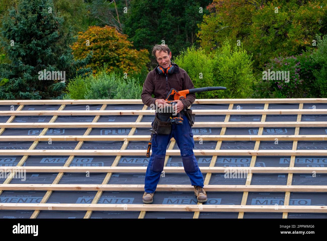 Workman standing on roof after completing gathering over insulation of ...