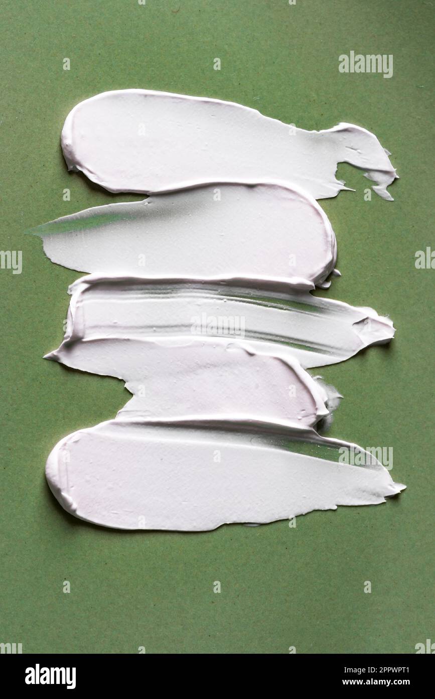 White skincare product smear of cream or face mask on green background ...