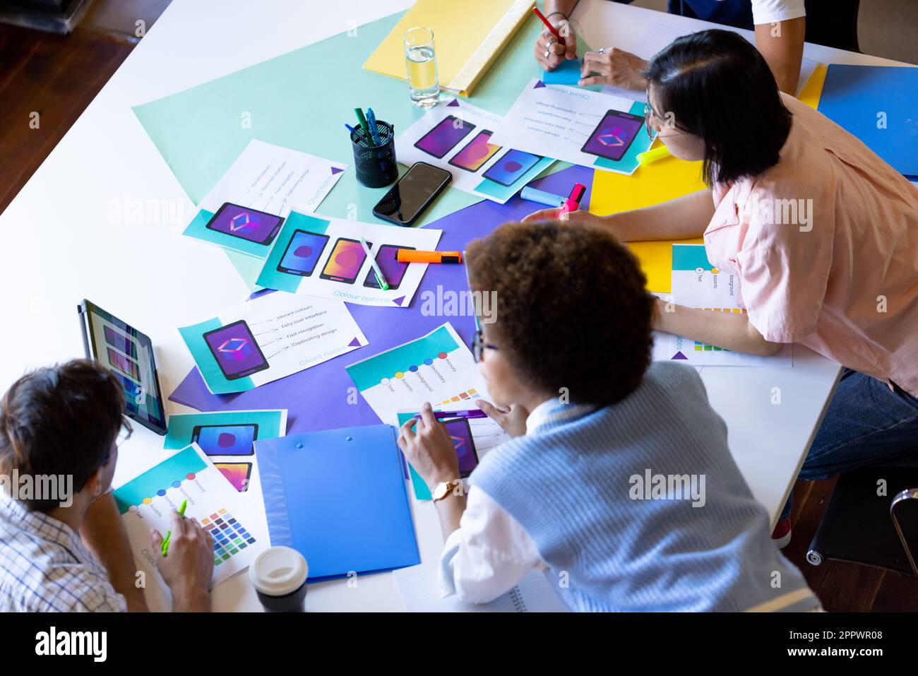 High angle of busy diverse designers using tablet and discussing ...