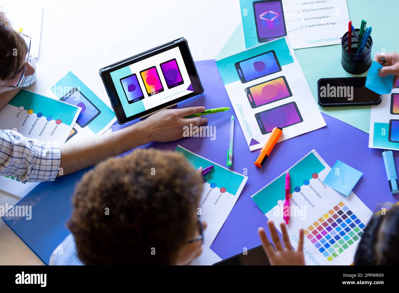 High angle of busy diverse designers using tablet and discussing ...