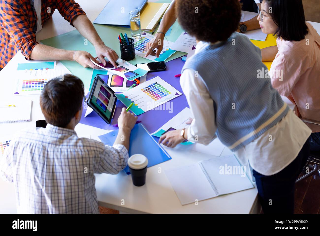 High angle of busy diverse designers using tablet and discussing ...