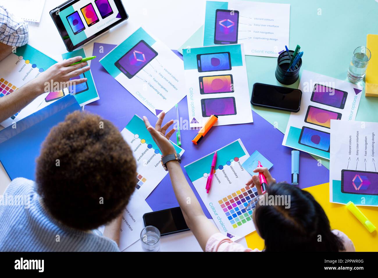 High angle of busy diverse designers using tablet and discussing ...