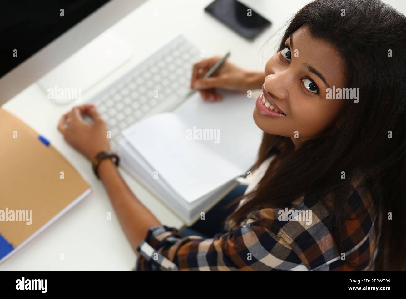 Smiling African American woman takes notes and writes in notebook Stock ...