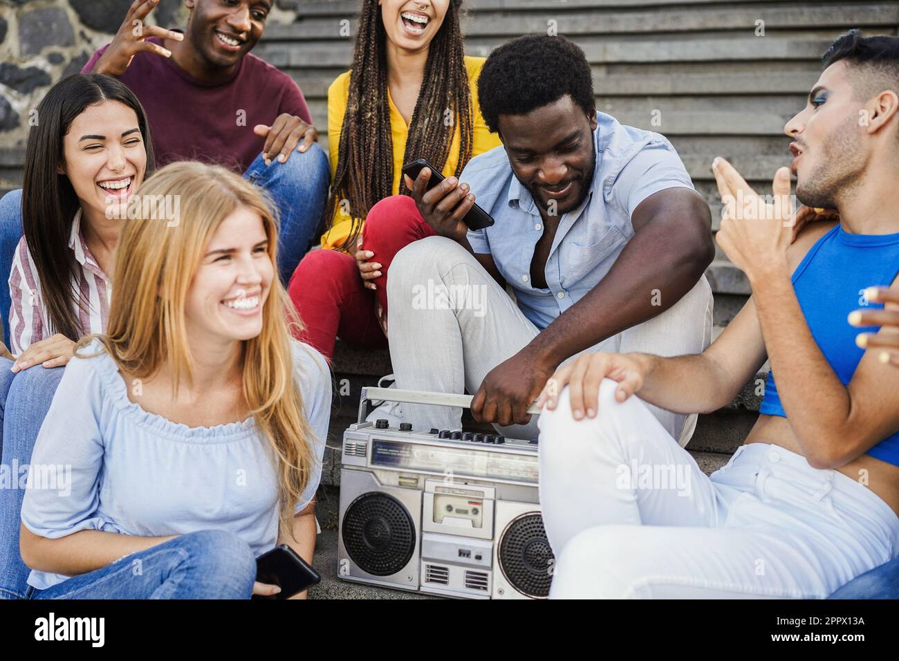 Young diverse people having fun listening music with boombox stereo ...