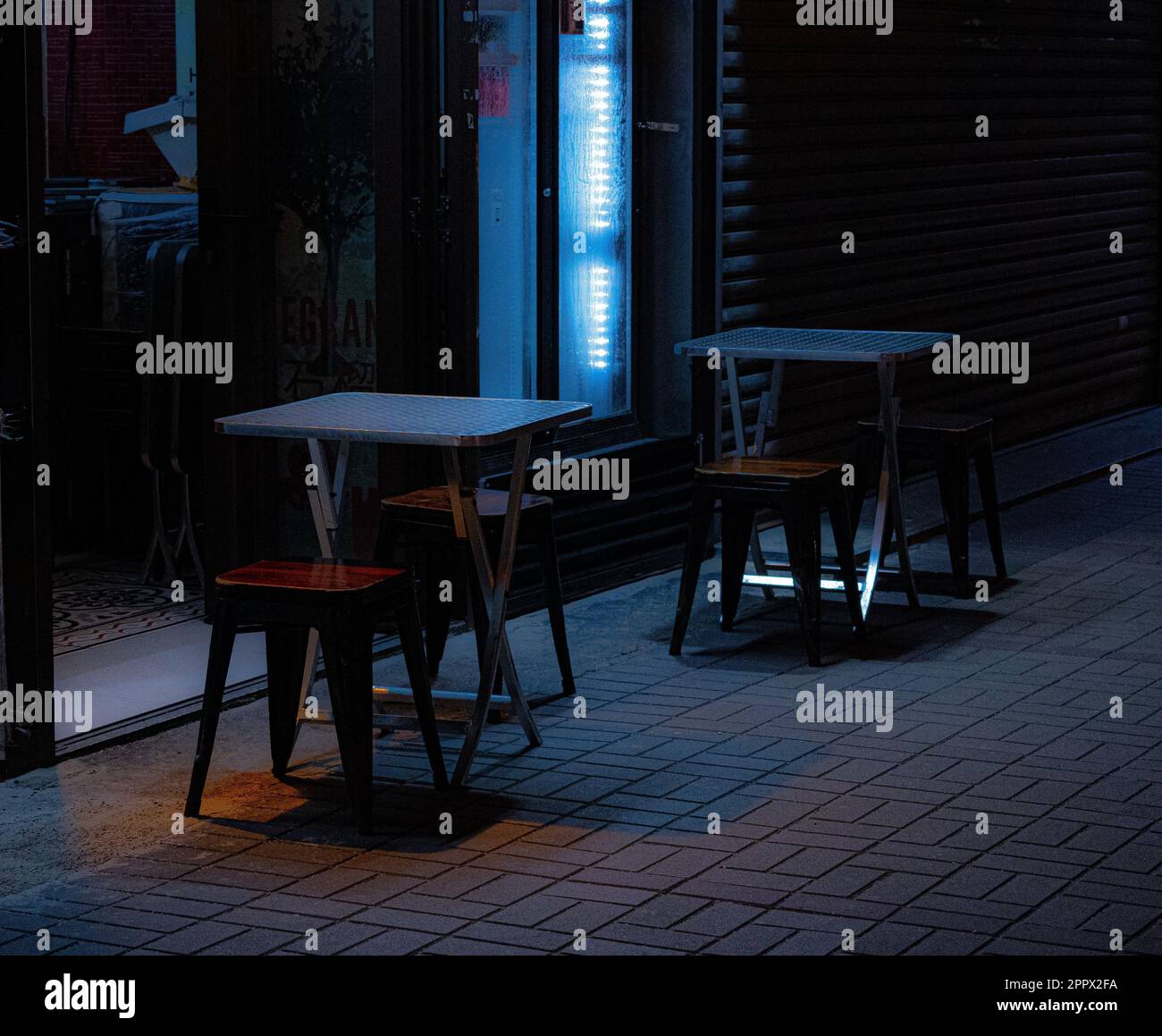 Empty chairs and tables outside of a cafe at night Stock Photo - Alamy