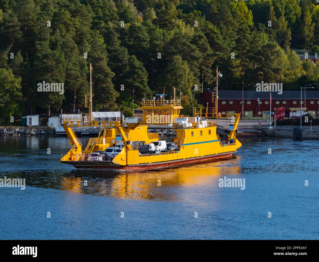 Vaxholm, Sweden - Sep, 2022: Yellow ferry with cars crosses the strait ...