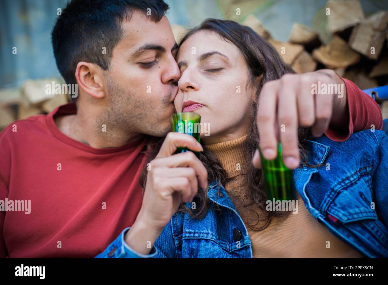 A very drunk hugging couple in love kissing and enjoying. Drink a strong alcoholic drink from ...