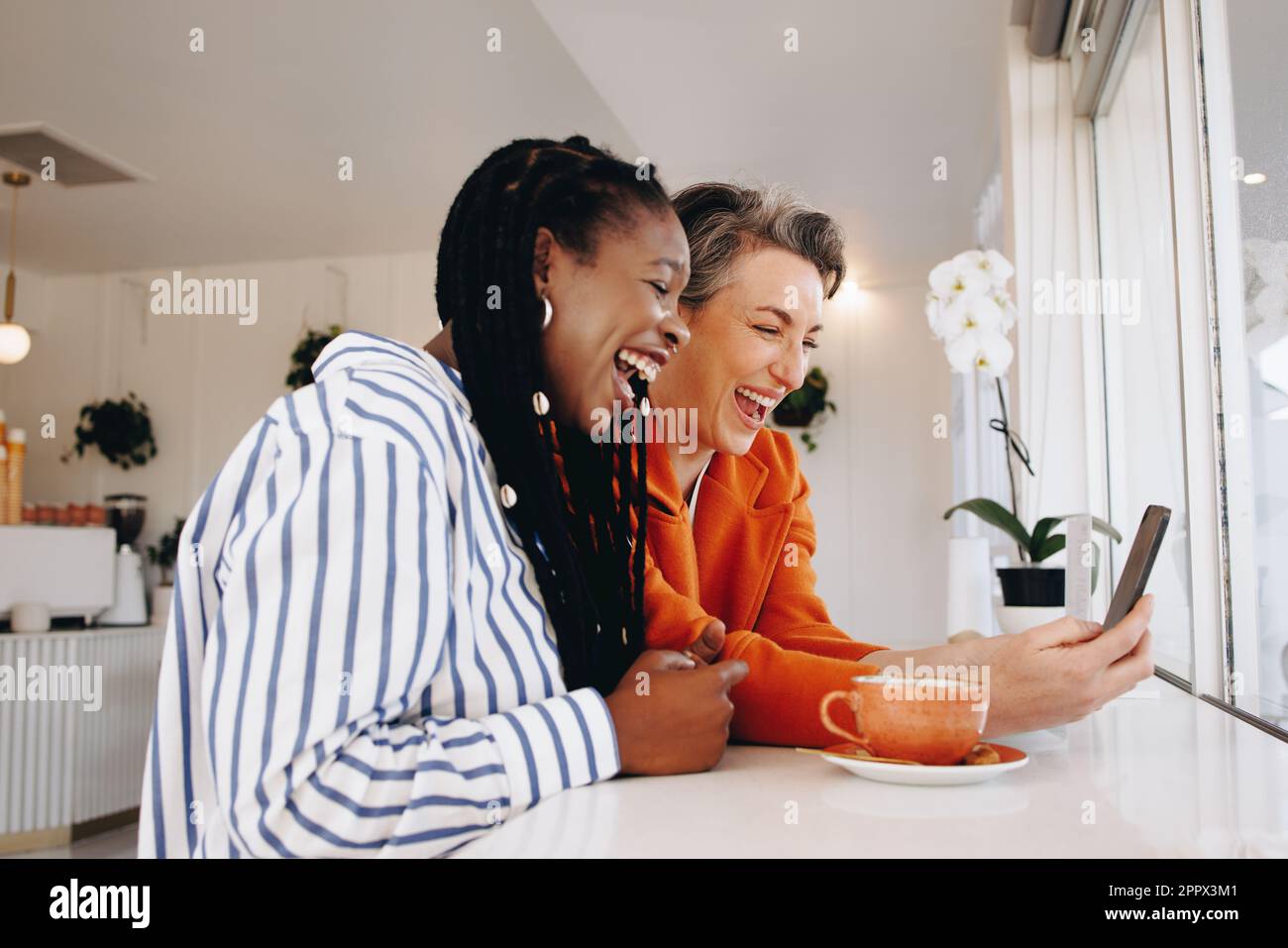 Two happy business women video calling their colleagues on a smartphone ...