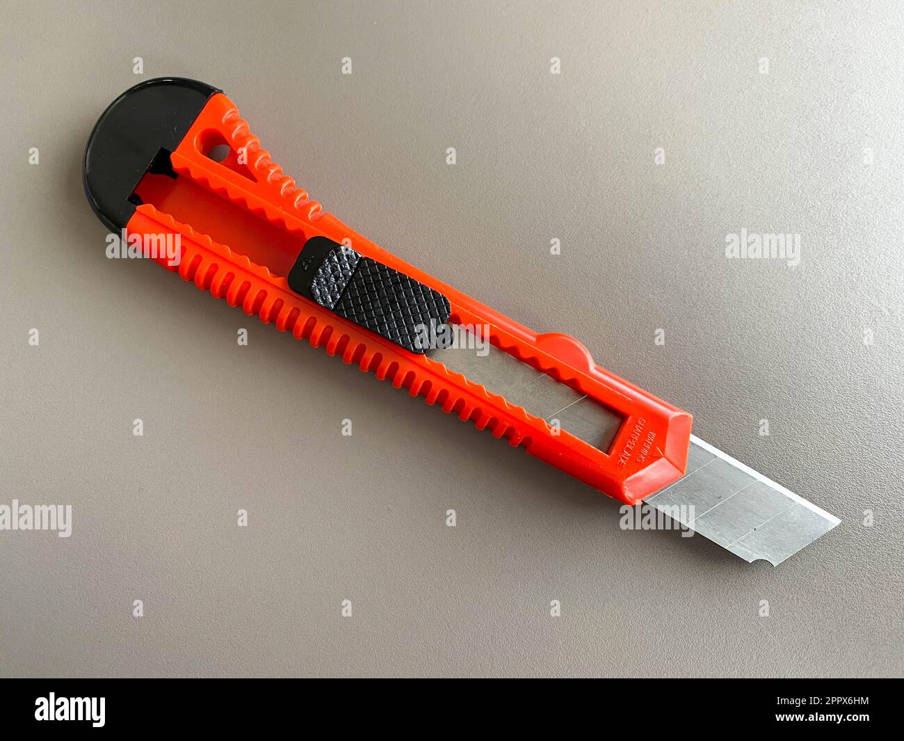 Red sharp office stationery knife with a paper cutting blade on a ...