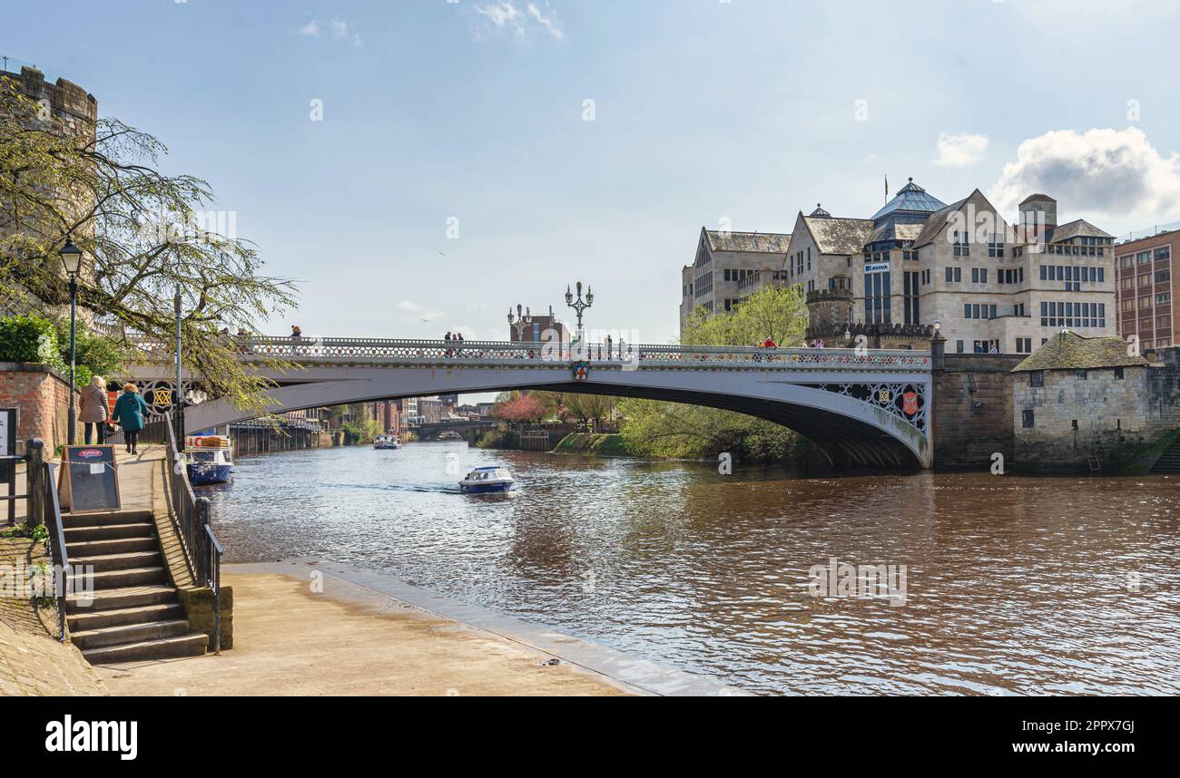 A historic iron bridge with a small boat passing underneath. A modern ...