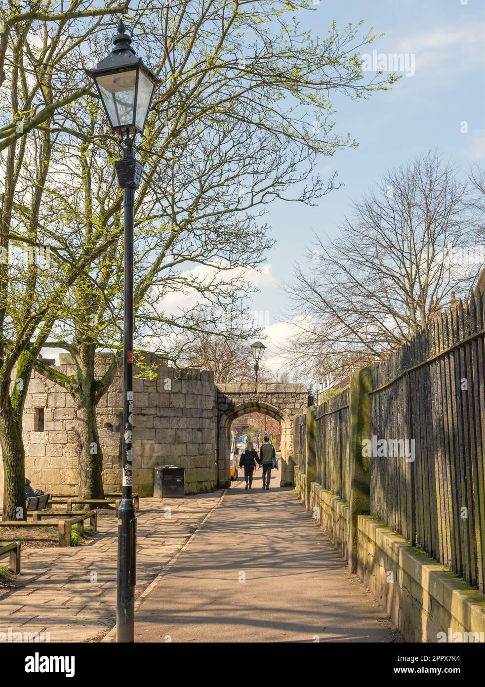 A path leading to an ancient tower with an arch. A couple walk under ...