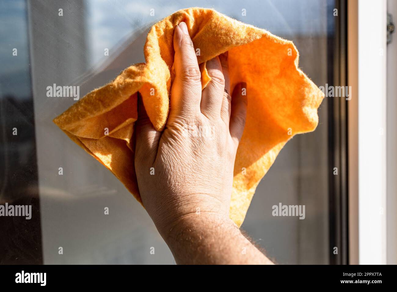 male hand wipes surface of window glass with rag in urban house on ...