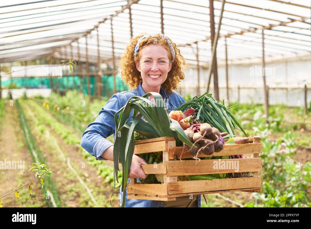 Happy female farmer carrying vegetables crate while working at farm Stock Photo - Alamy