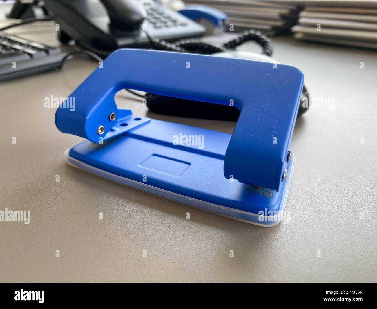 Blue iron metal office punch for punching holes in sheets of paper and ...