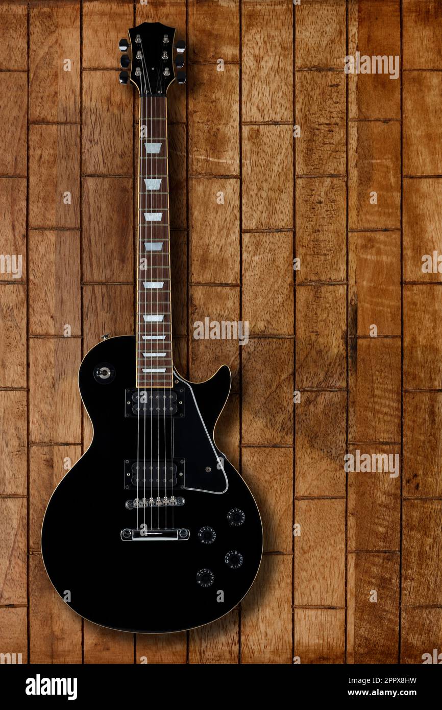 Black electric guitar on a distressed wooden backdrop with spoace for ...