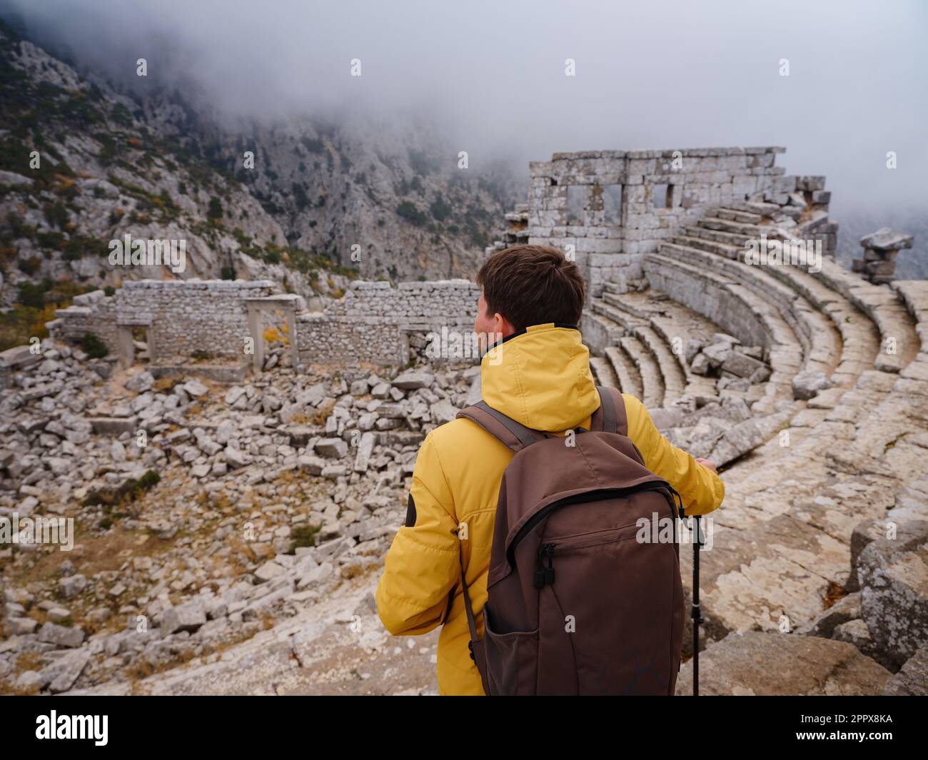 Autumn walk , man in yellow jacket looks at the ancient amphitheatre in ...