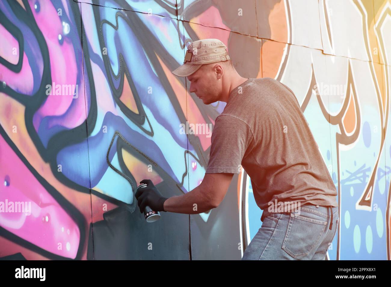 Young caucasian male graffiti artist drawing big street art painting in ...