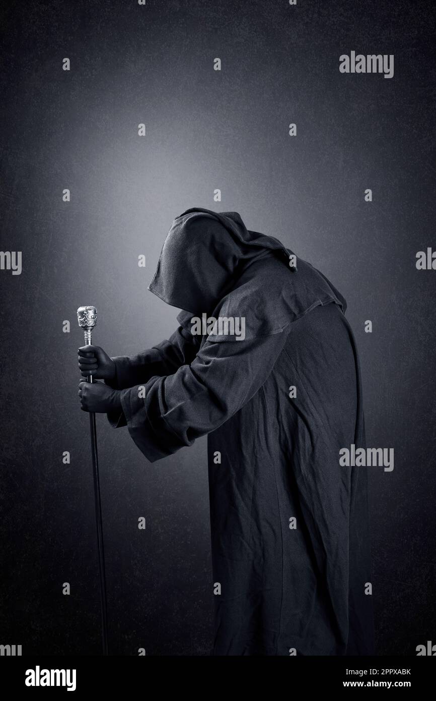 Wizard with hooded cape and magic staff over dark misty background ...