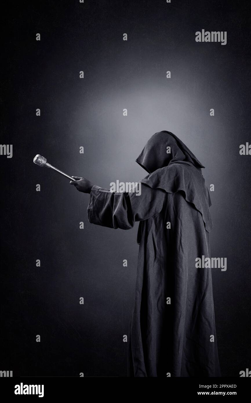 Wizard with hooded cape and magic staff over dark misty background ...