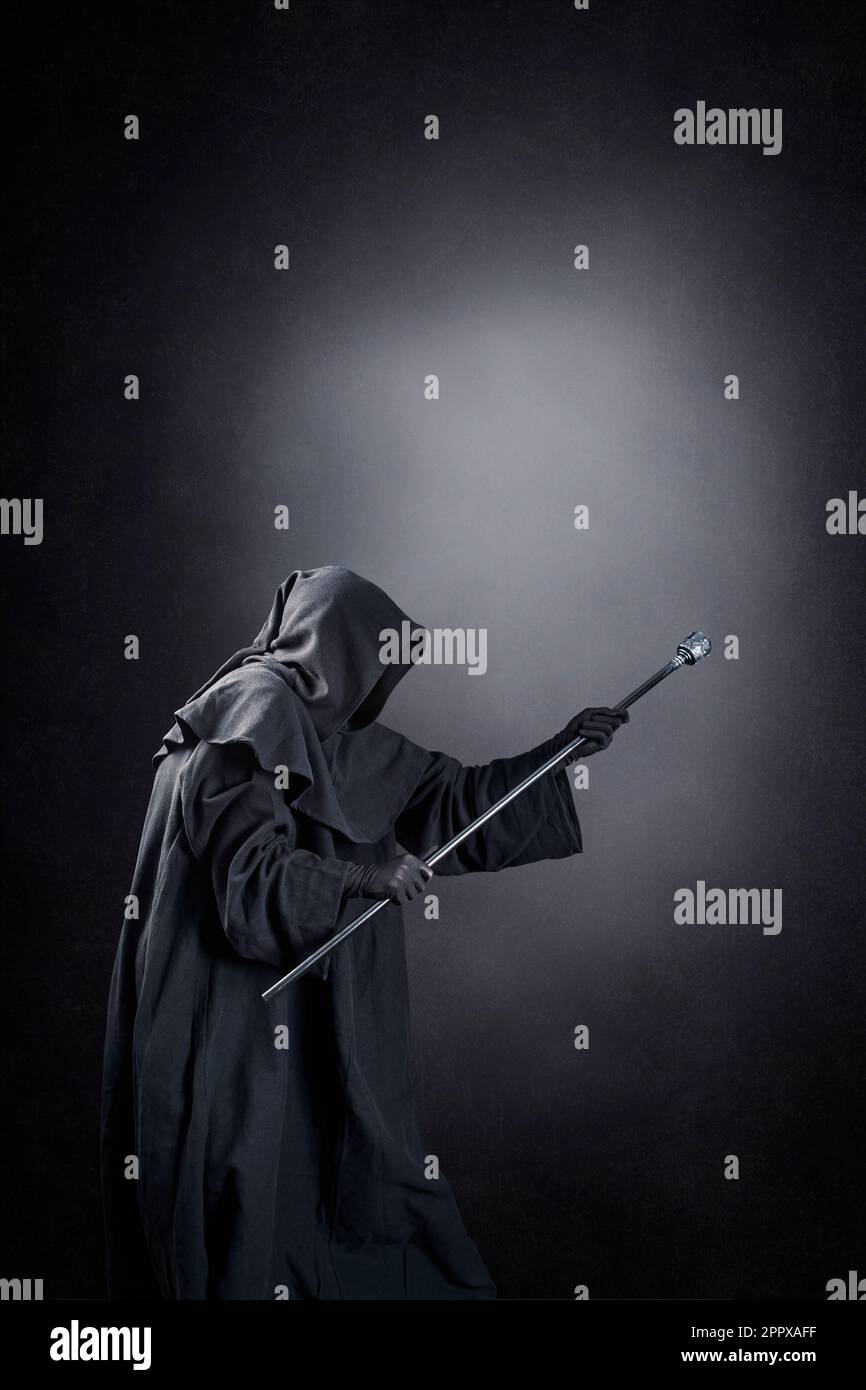 Wizard with hooded cape and magic staff over dark misty background ...