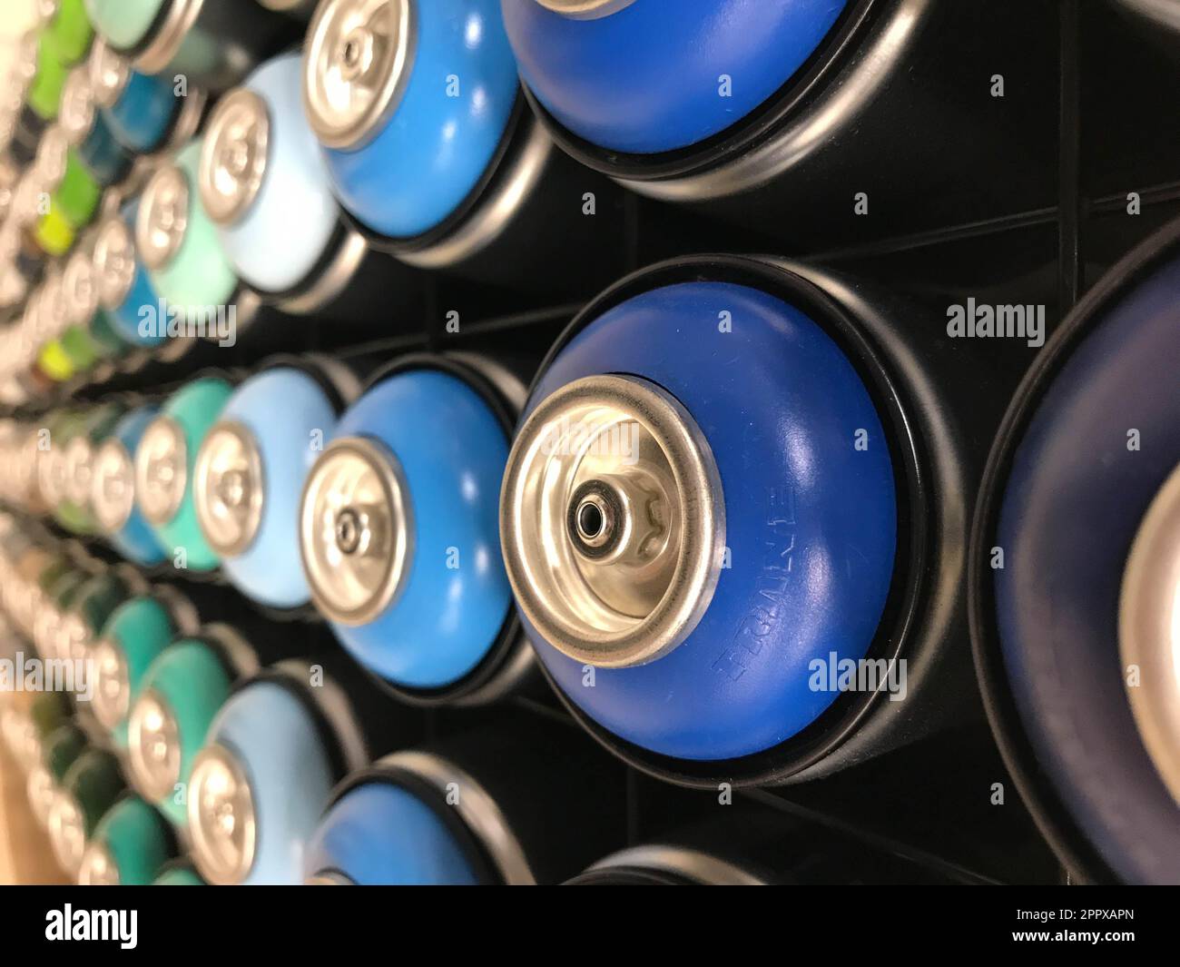 Rows of color paint spray cans placed on a black wall. Abstract colour ...
