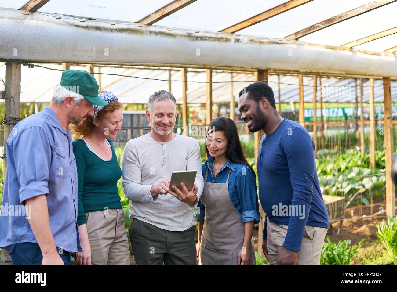 Smiling male agronomist explaining multicultural farmers over digital ...