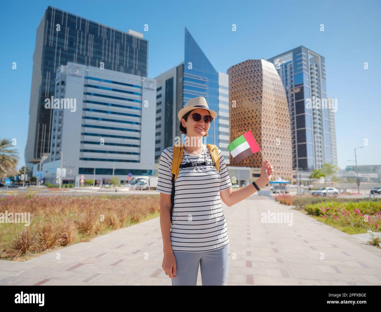 Happy young asian female traveler with backpack and hat with UAE flag ...