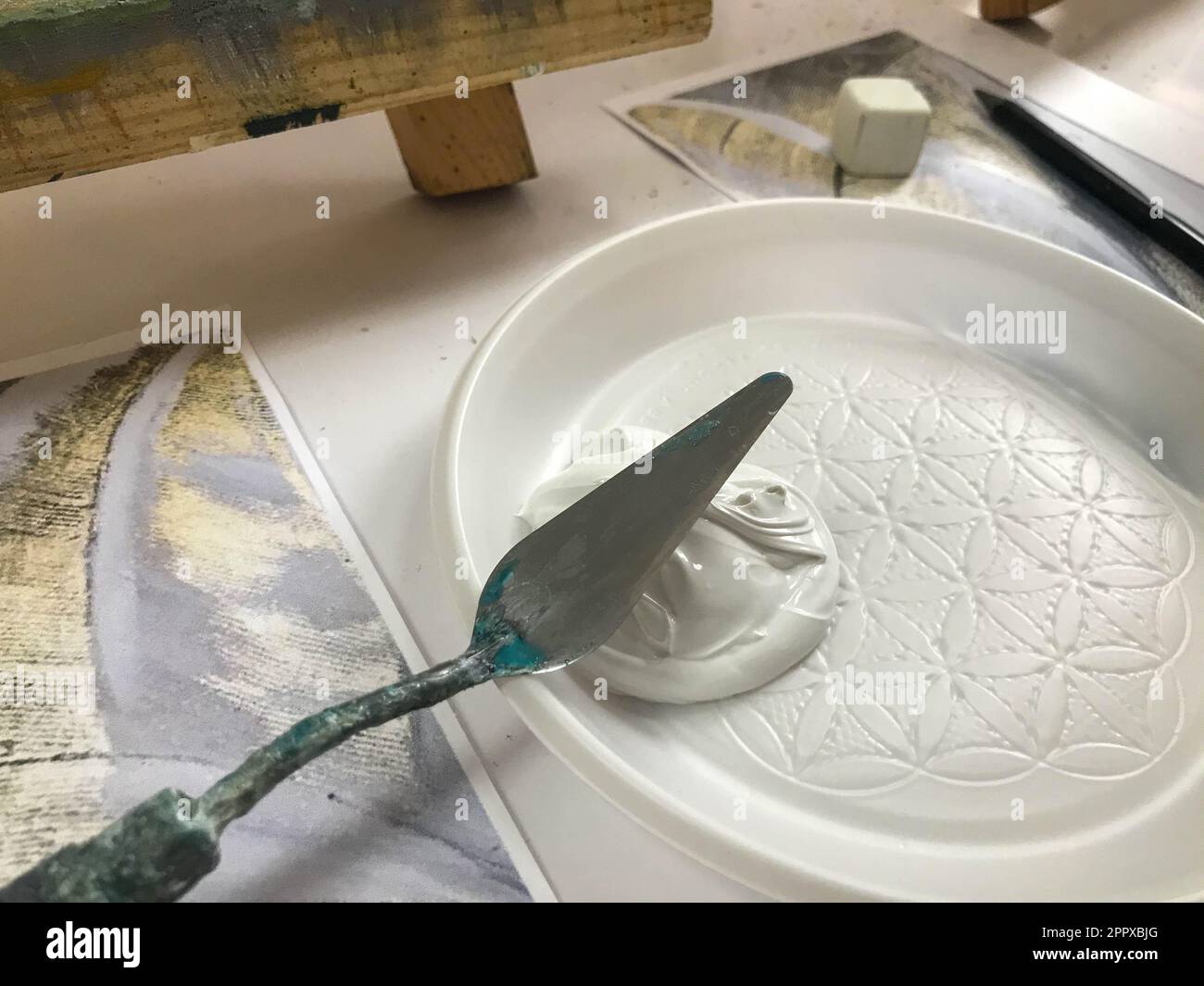 palette knife in the hand of an artist mixing acrylic paints of ...