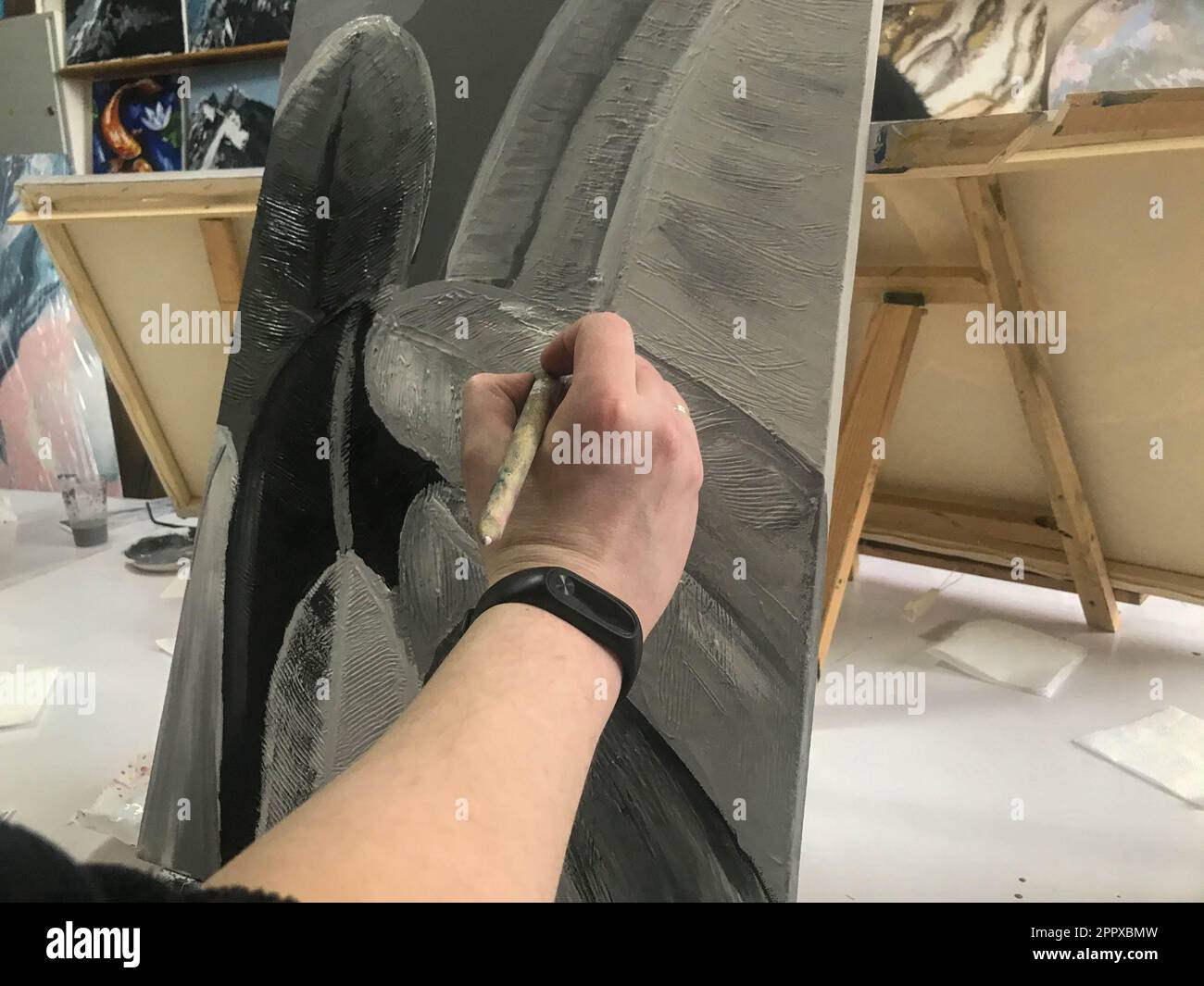 Artists hands with brush and paint, paints on easel, painting at studio ...