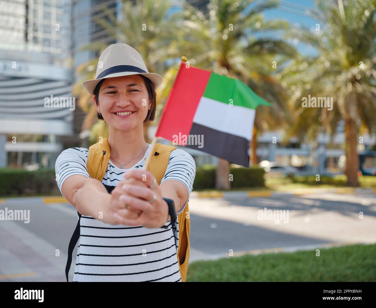 Happy young asian female traveler with backpack and hat with UAE flag ...