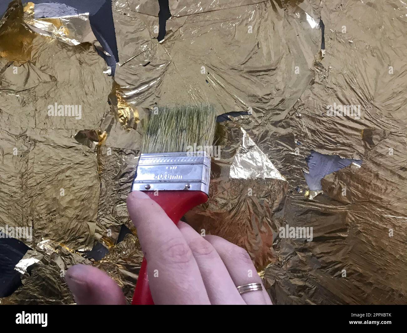 The artist's hand paints with a brush using gold glittering bright ...