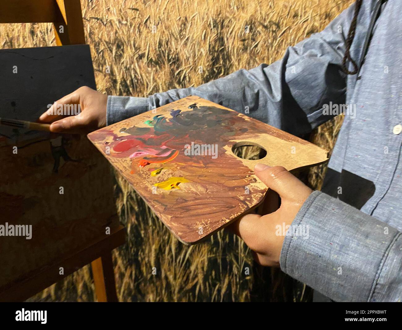 The artist holds a paintbrush in his hand, with which he mixes bright ...