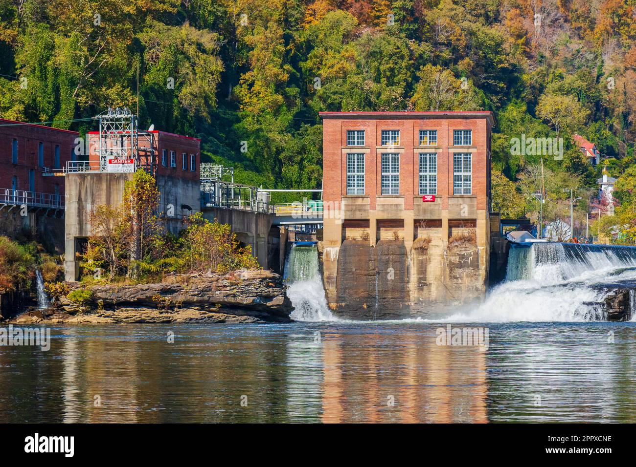 A large dam is situated on the edge of a river, with the water lapping ...