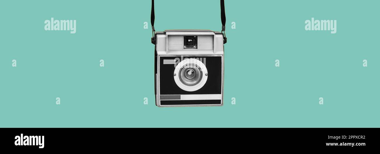 a gray and black retro film camera hanging from its straps on a blue ...