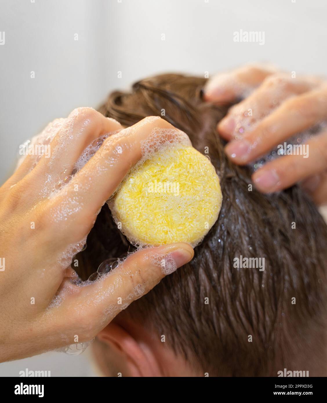 A man uses a solid shampoo bar in the bathroom. An applying shampoo to ...