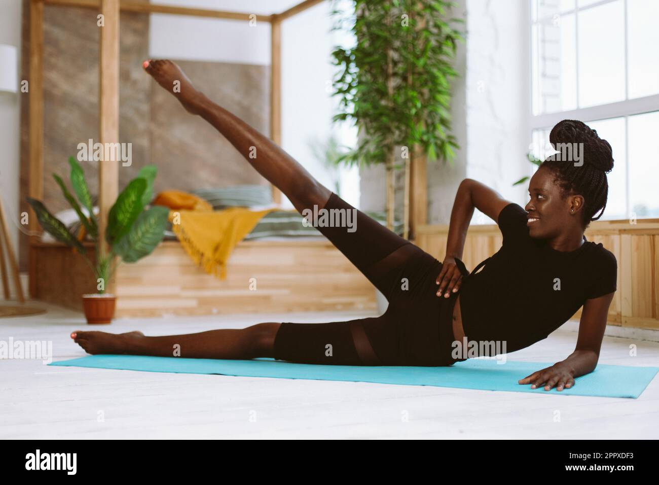 Beautiful athletic afro american woman lying on side and raising leg up ...