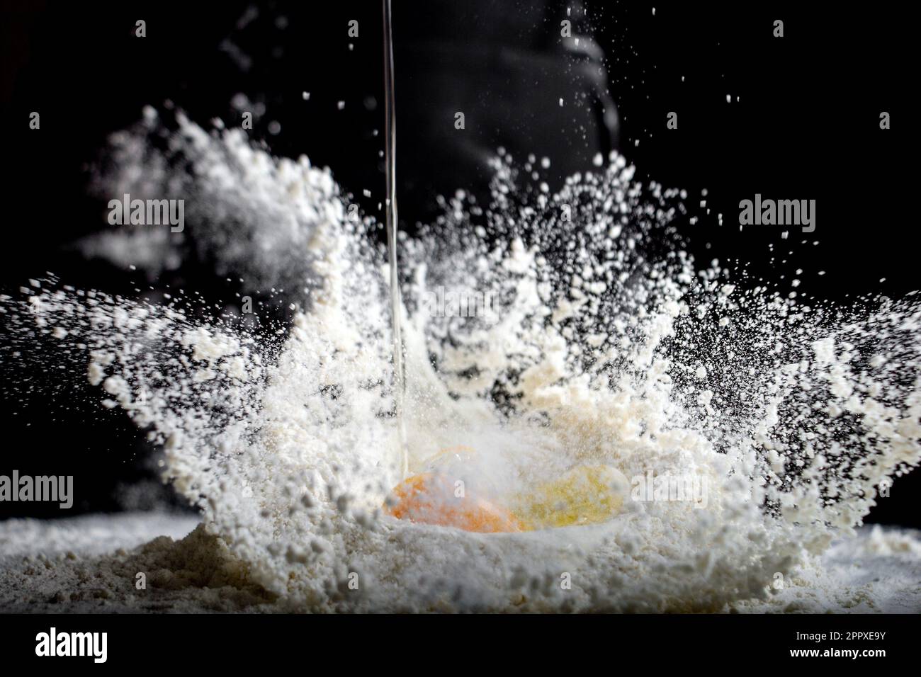 Close up view of yolk falling on flour on black background Stock Photo - Alamy