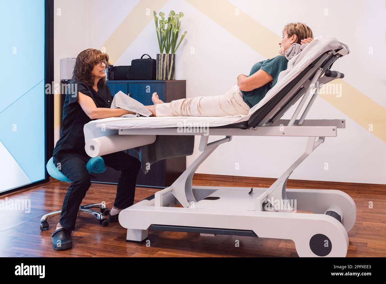 Side view of female physiotherapist sitting on bench while examining ...