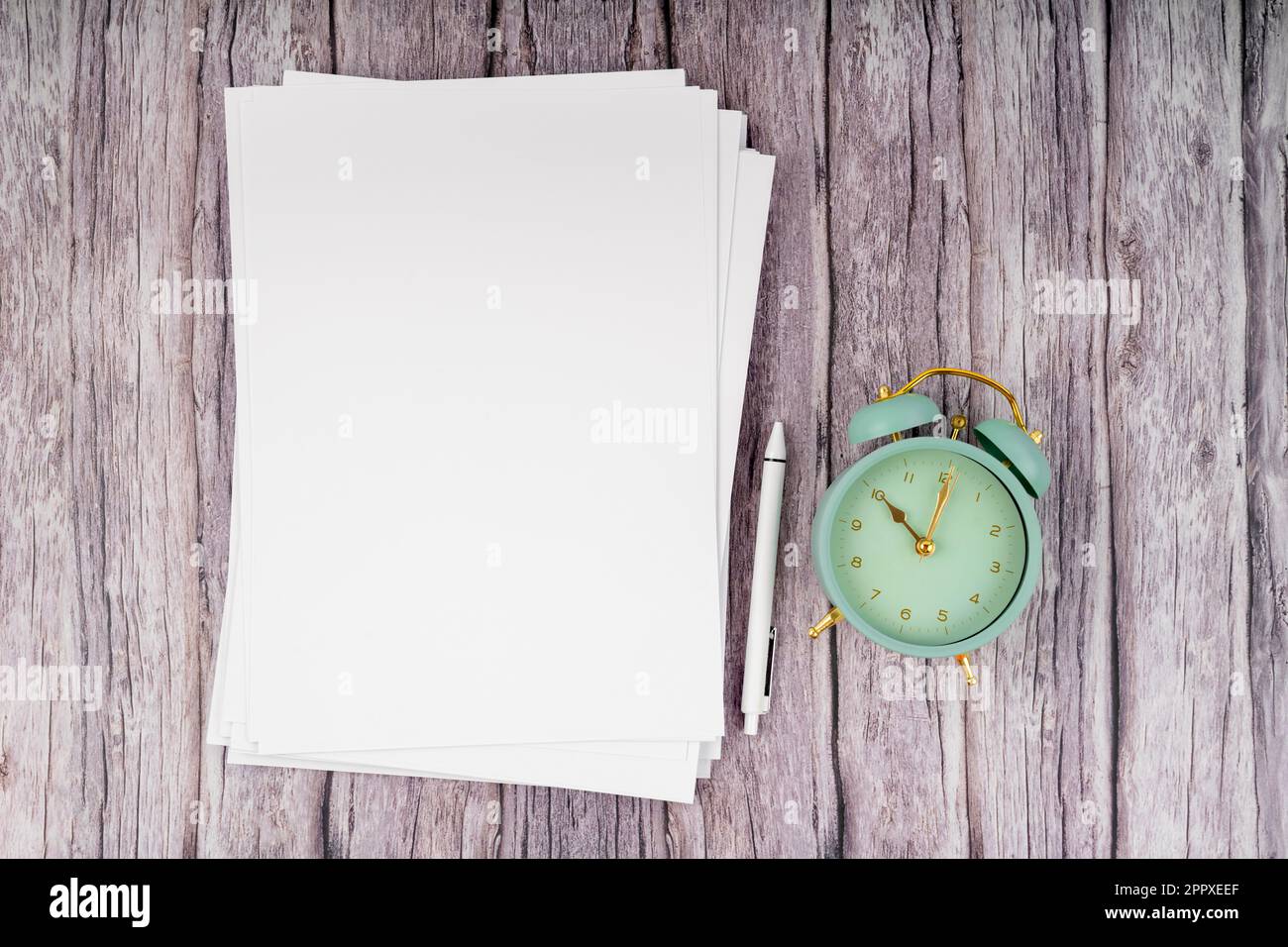 Top view of heap empty A4 paper and vintage alarm on wooden background ...