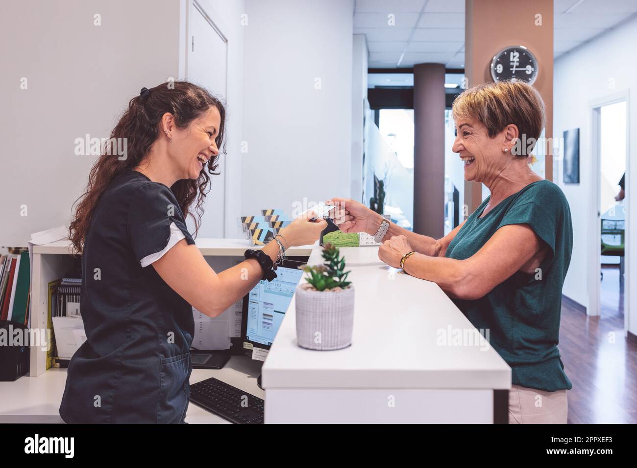 Side view of middle aged female patient standing at reception counter ...