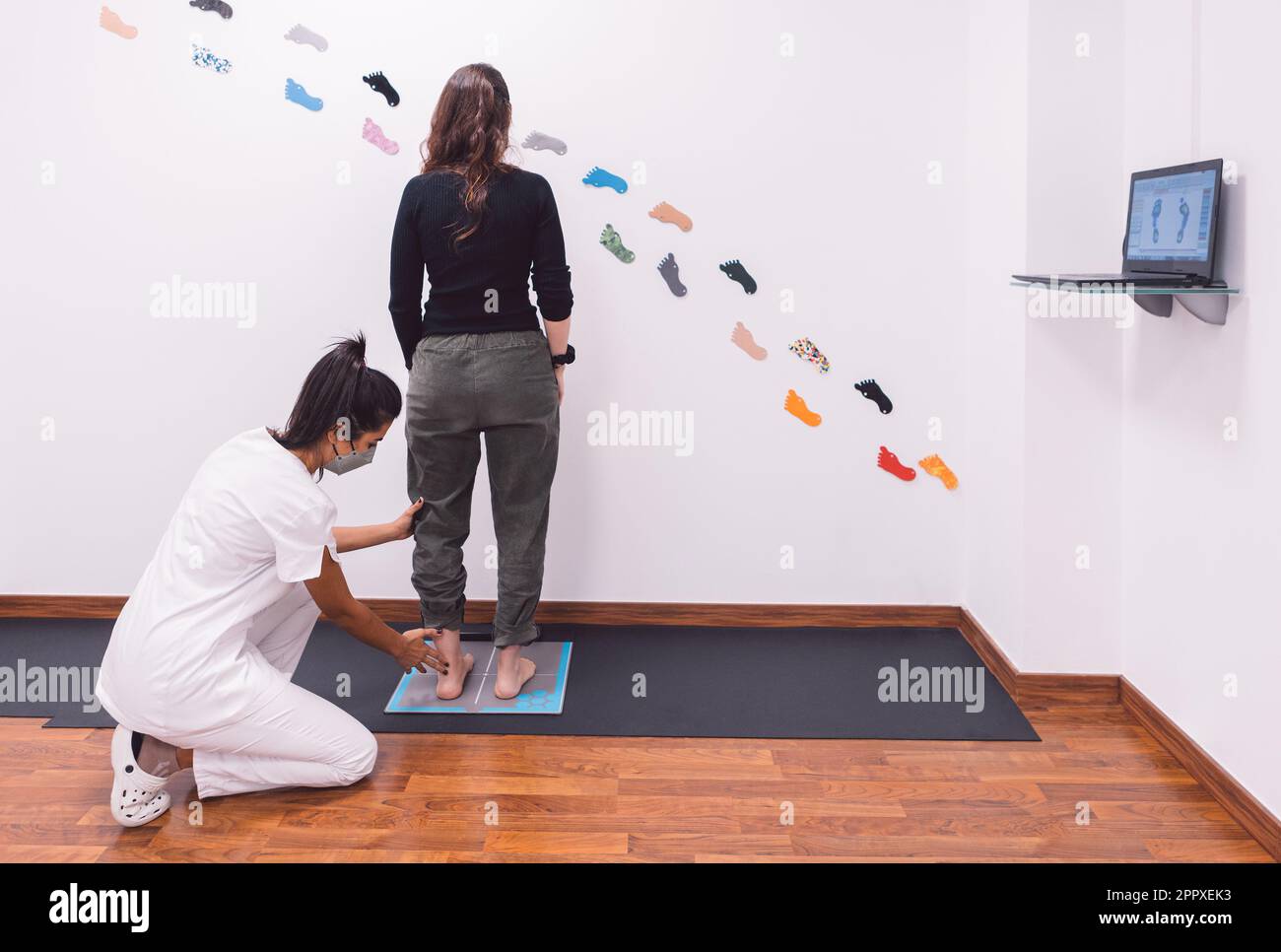 Focused female podiatrist in medical uniform and mask measuring foot of ...