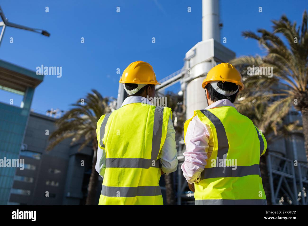 Low angle back view of anonymous engineers in protective helmet and ...